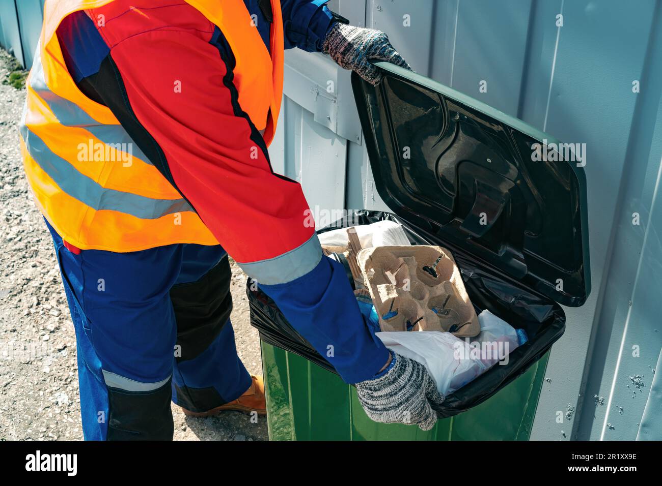 Male janitor in uniform cleans a trash can in the street Stock Photo ...