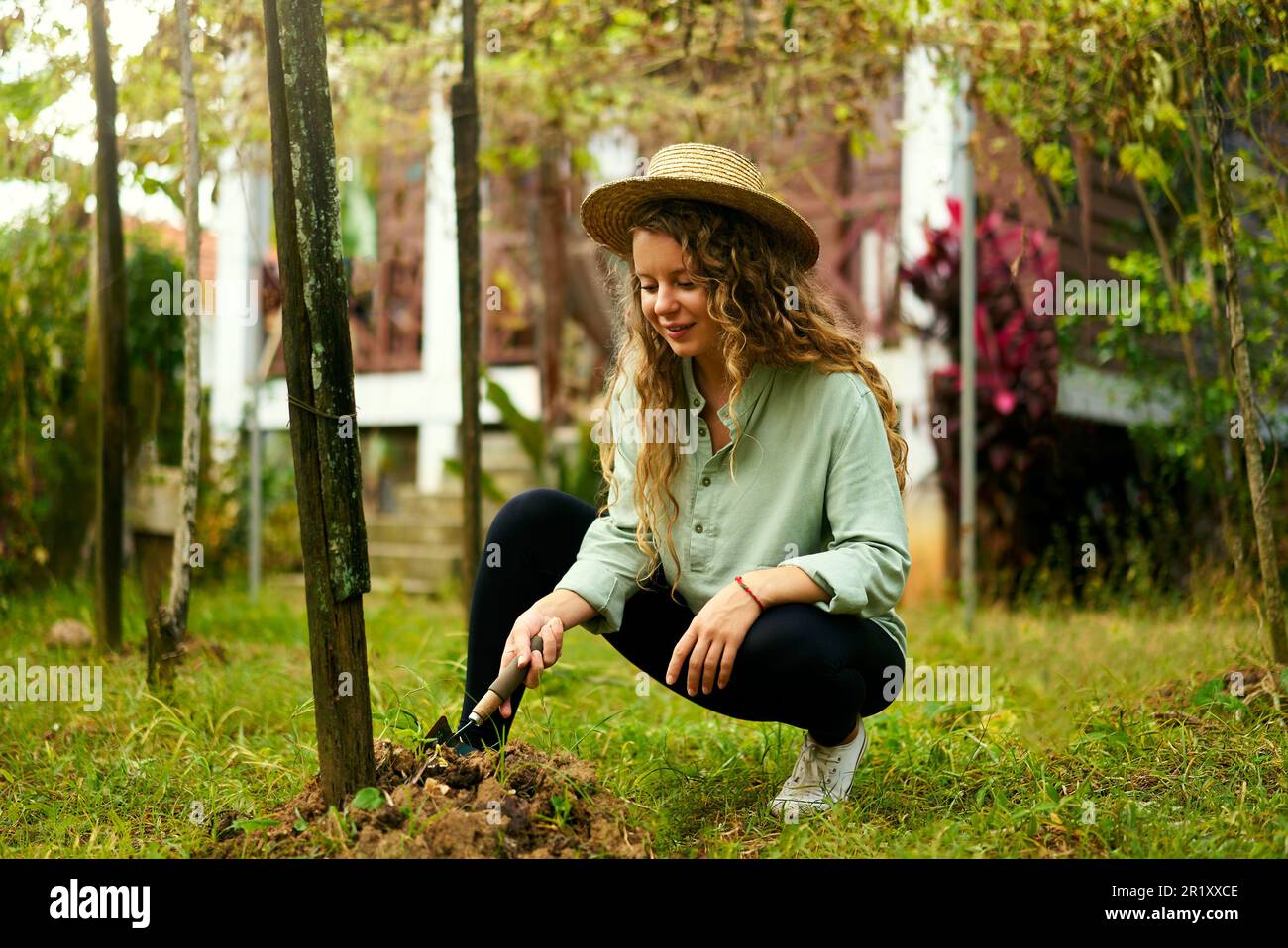 Young caucasian female farmer loosening the soil with garden shovel ...