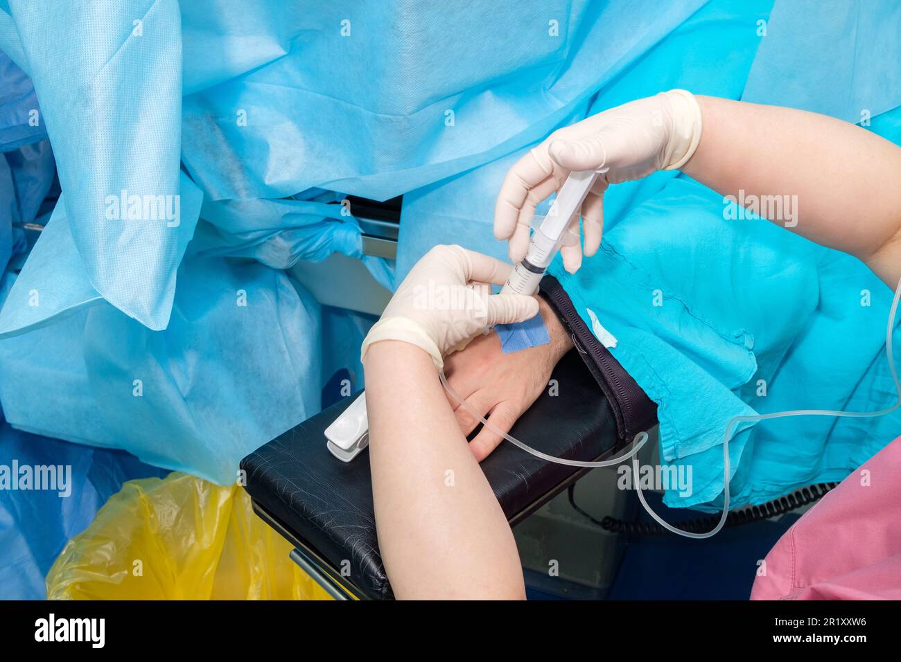 The doctor injects anesthesia with a syringe into the arm of a patient ...