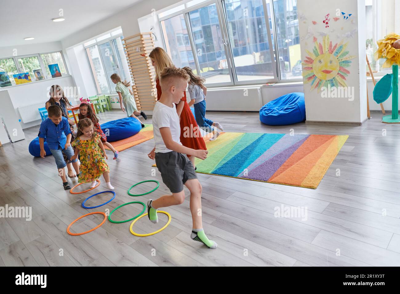 Small nursery school children with female teacher on floor indoors in ...