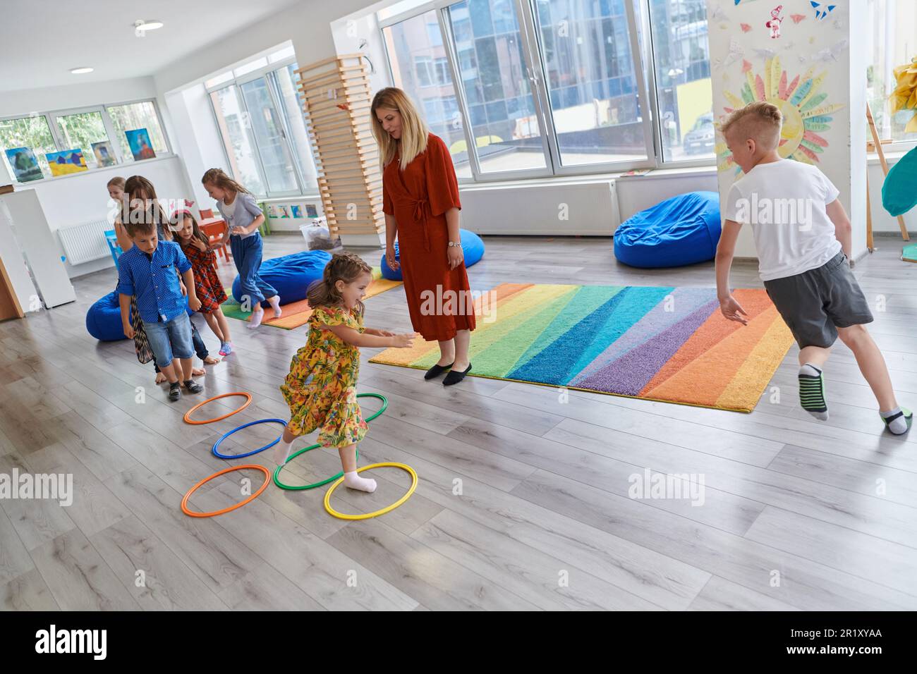 Small nursery school children with female teacher on floor indoors in ...