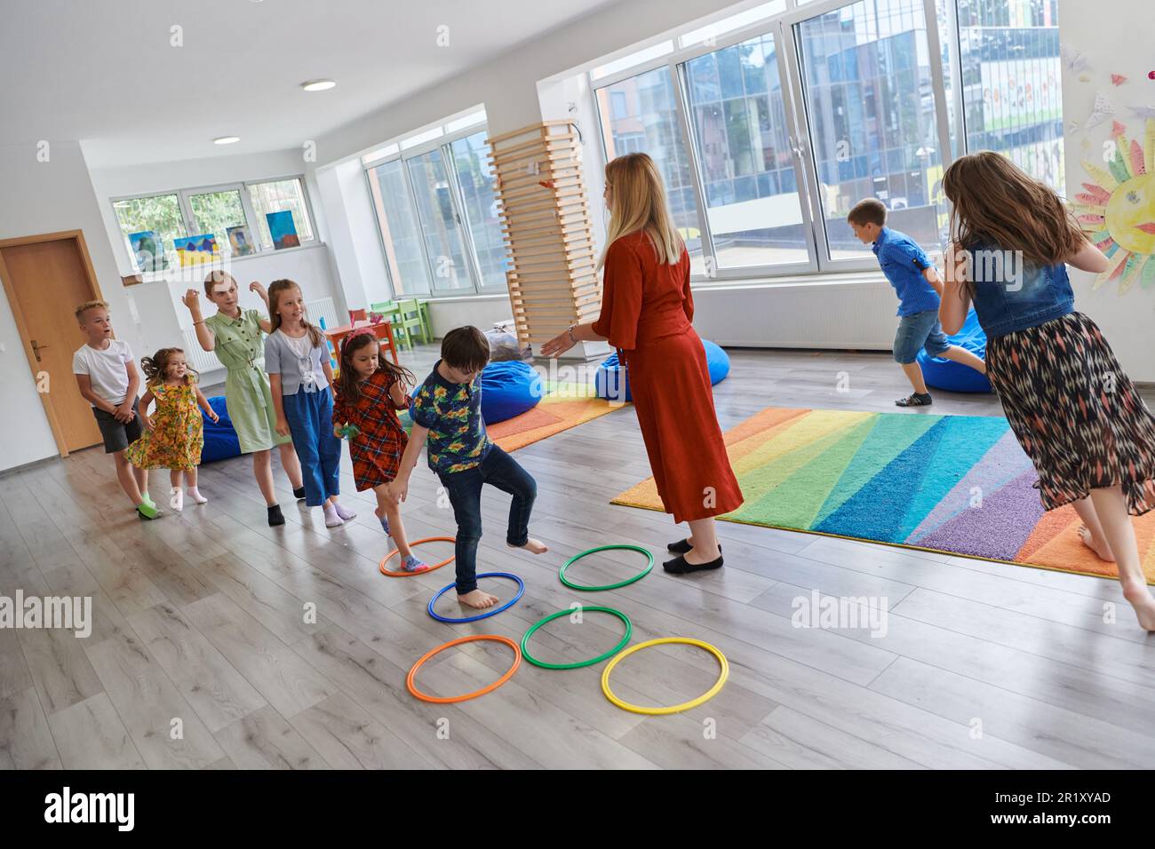 Small nursery school children with female teacher on floor indoors in ...