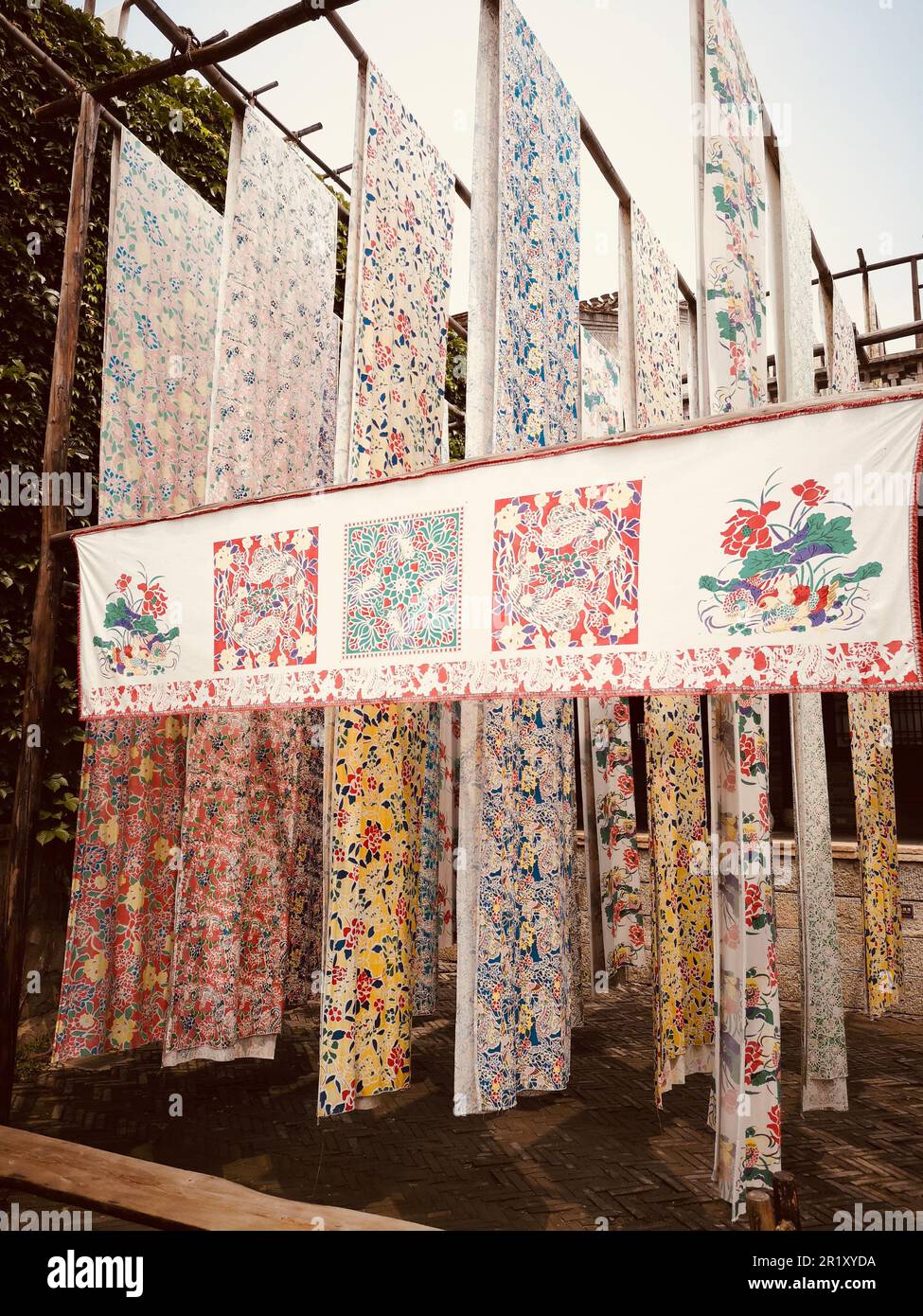 A colorful array of silk fabrics hanging from wooden poles in a vibrant ...