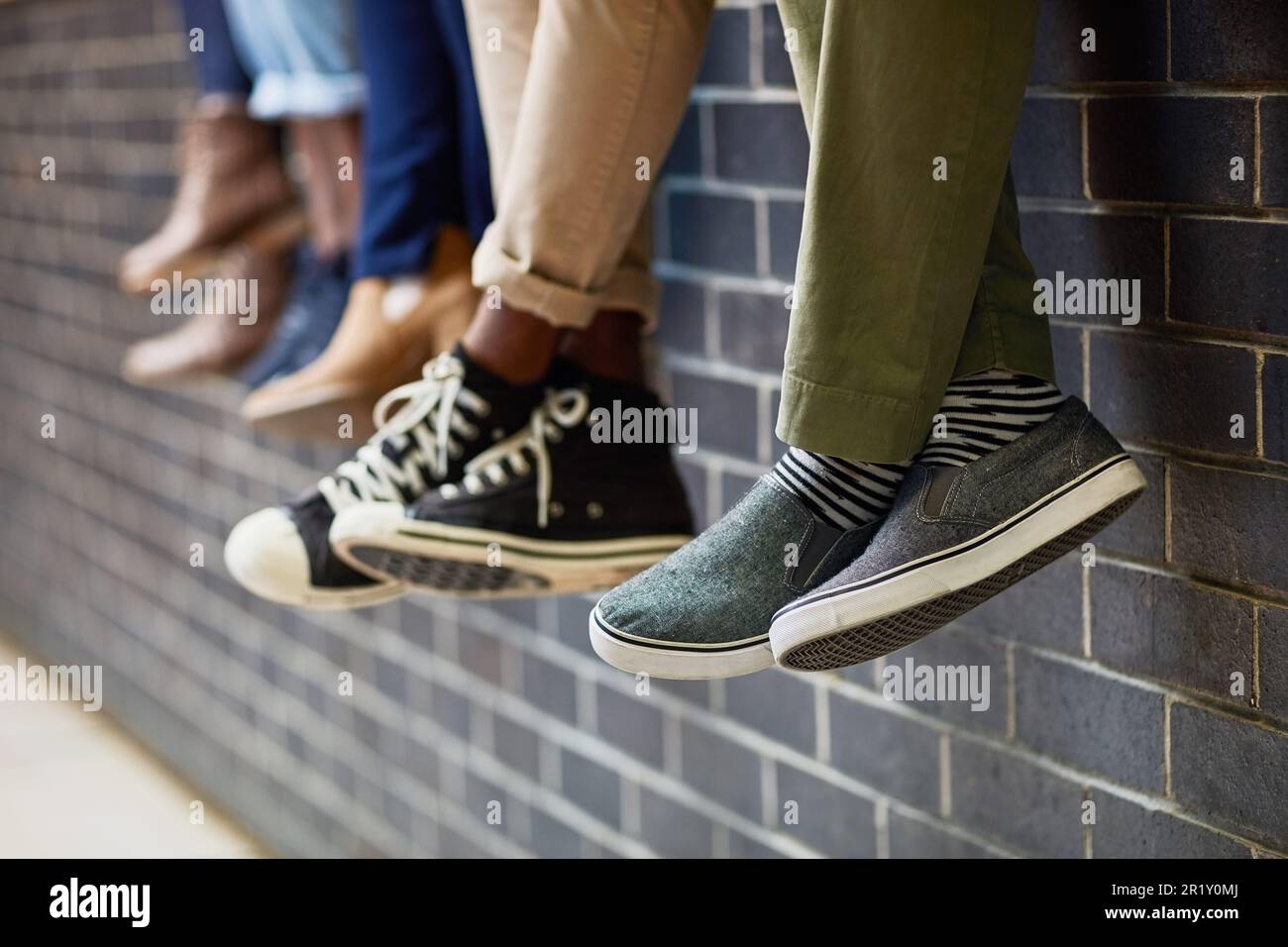 Brick wall, students feet and friends outdoor on university campus ...