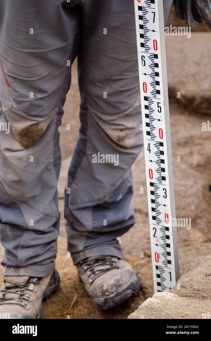 Worker holdings a telescopic leveling lath is helping surveyor ...