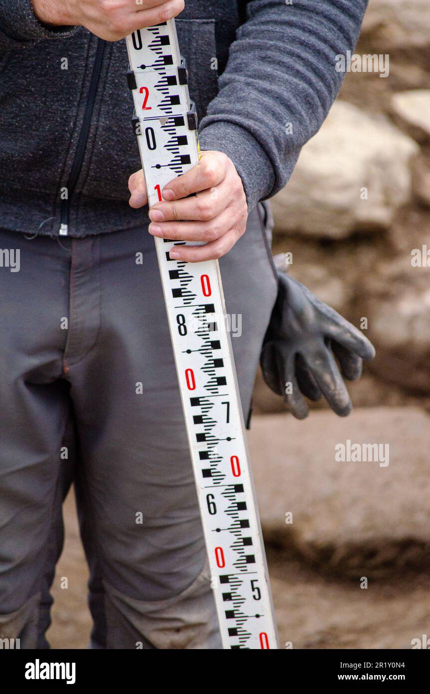 Worker is holding leveling rod to measuring level on construction site ...