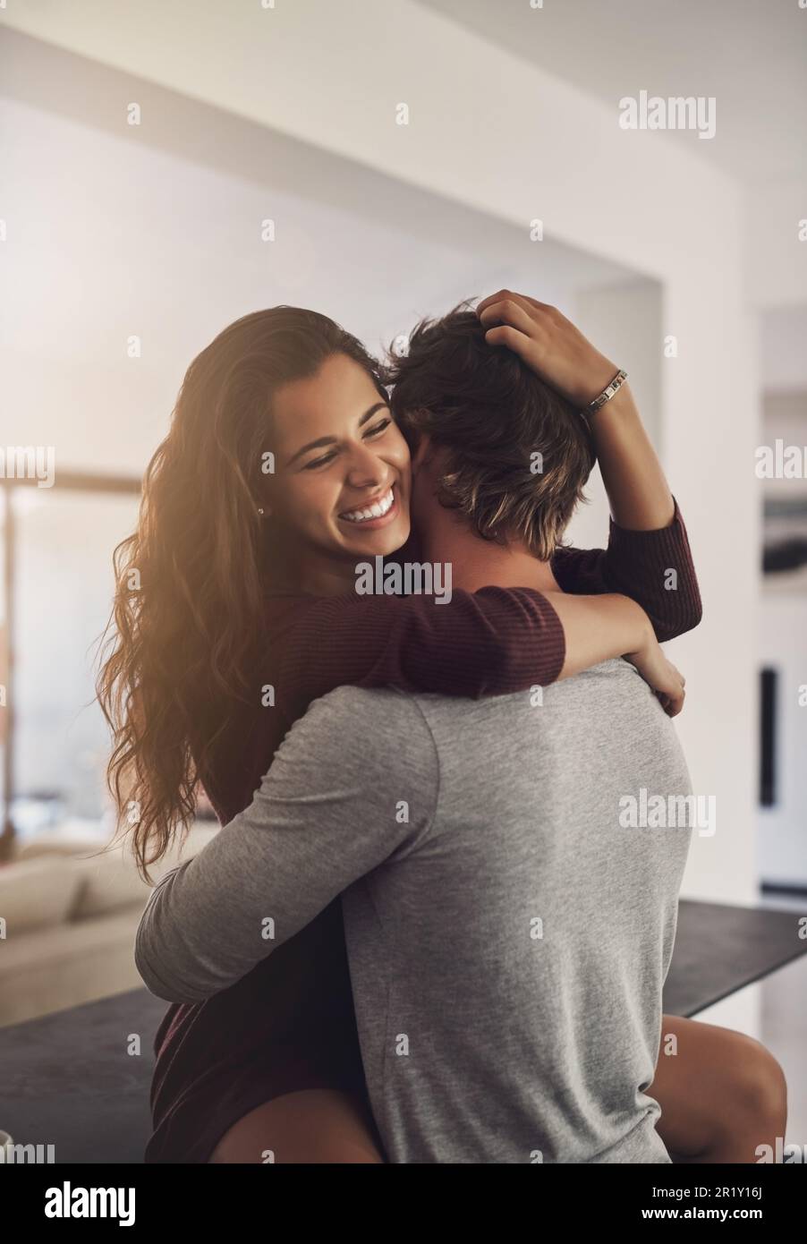 Happy young couple hugging in home for love, romance and caring bond ...