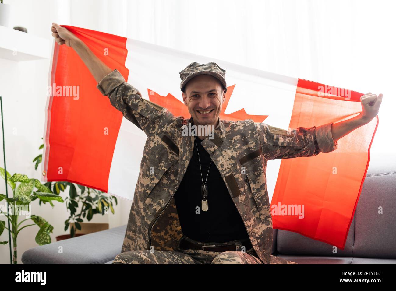 man in military uniform holding canada national flag while Stock Photo ...