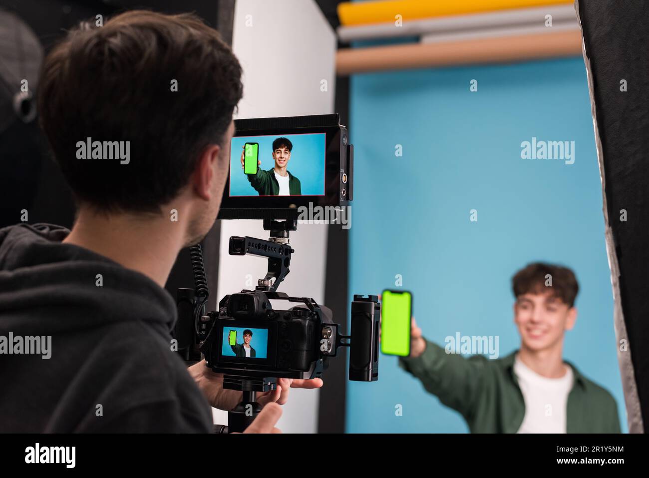 View of a professional photographer shooting a young man showing ...