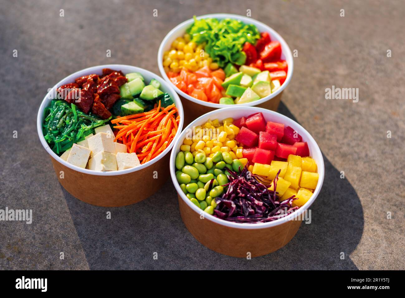 Close view of three poke bowls with vegetables, fruits, fish and ...