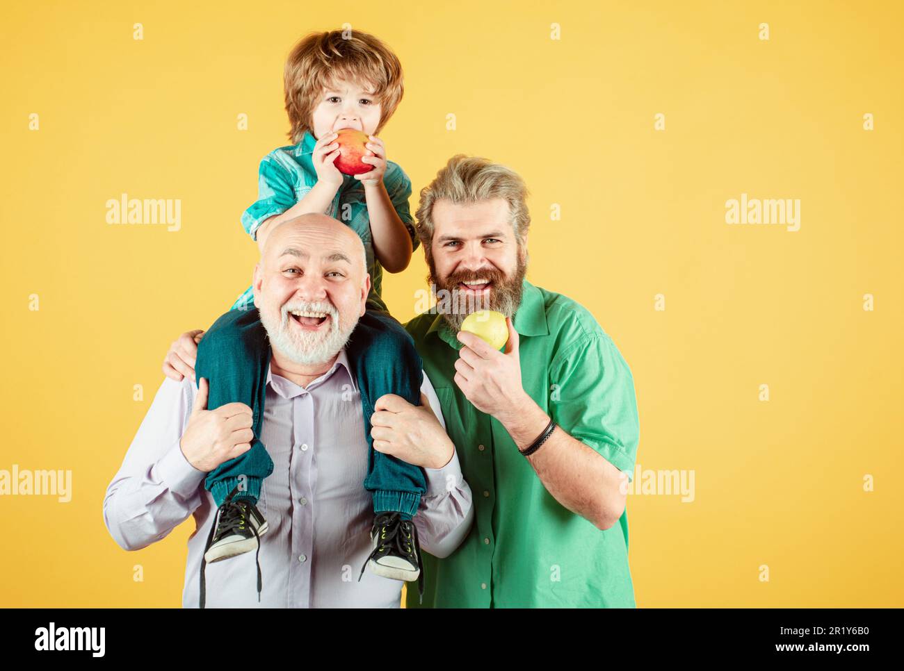 Grandfather father and son hugging and eating apple. Men in different ...