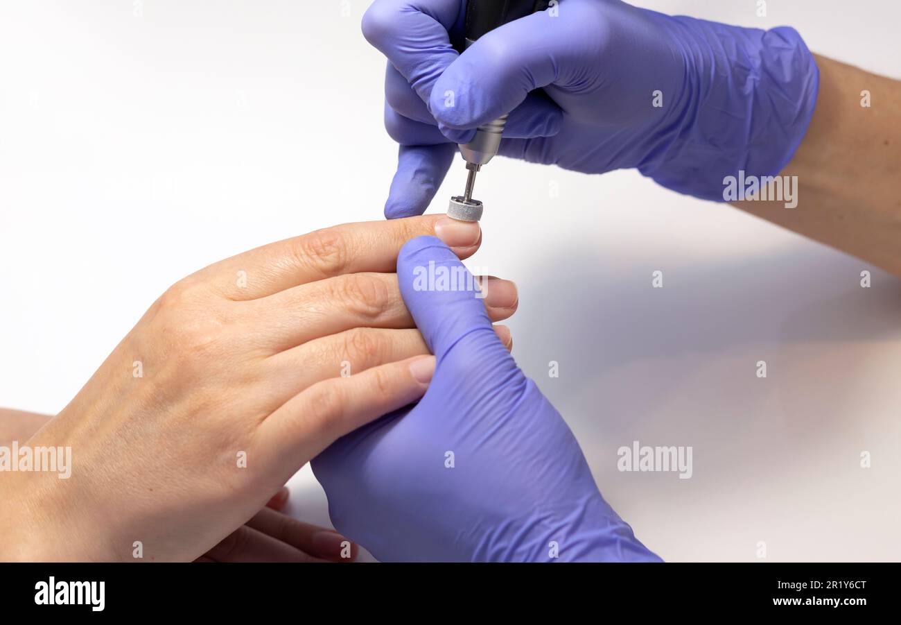 Nail beautician gloss client's fingernails by rubbing beeswax cream ...