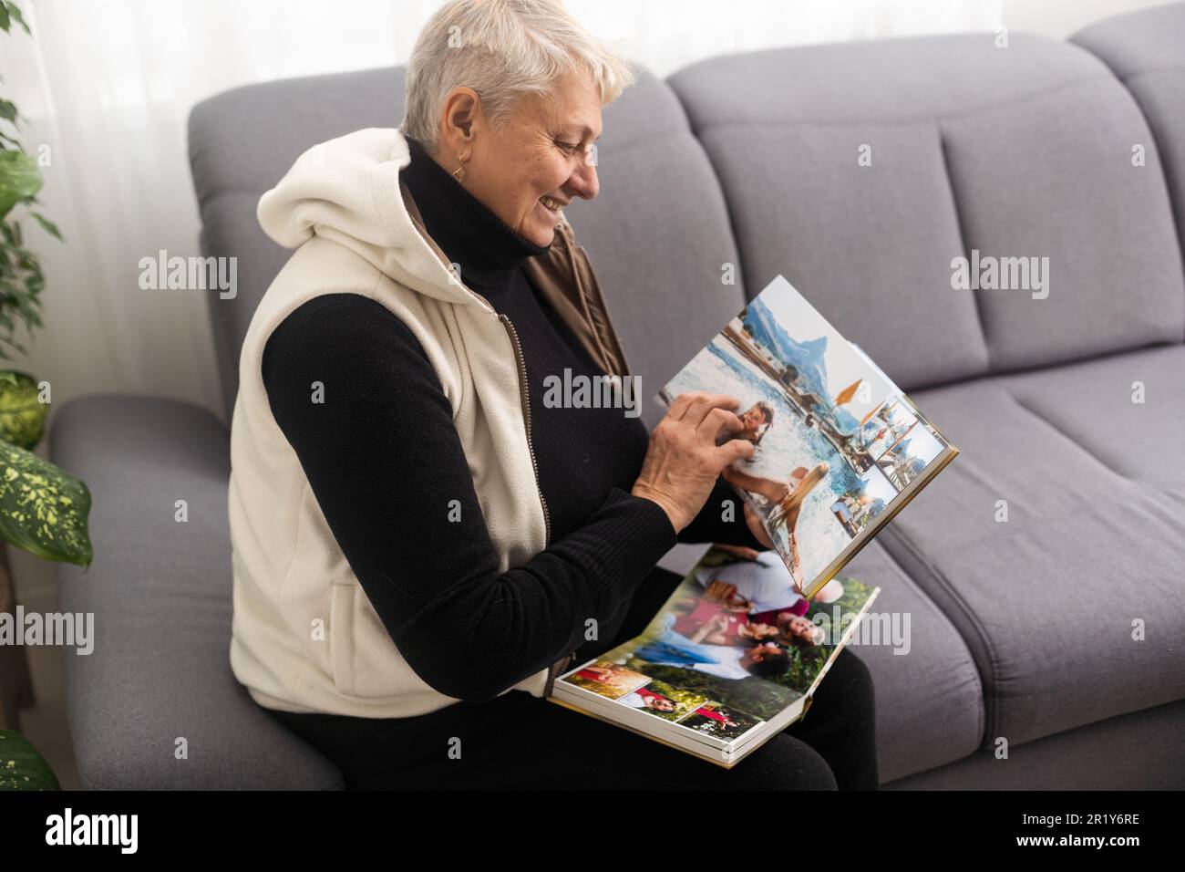An elderly woman with nostalgia looks at old photos in a photo album or ...