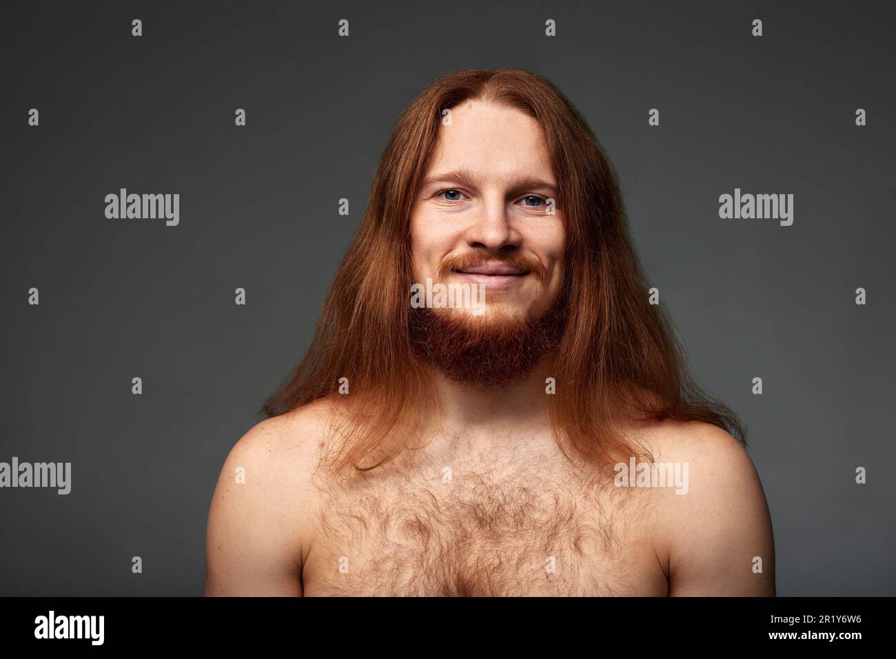Close-up studio portrait of a young red-haired man with long straight ...