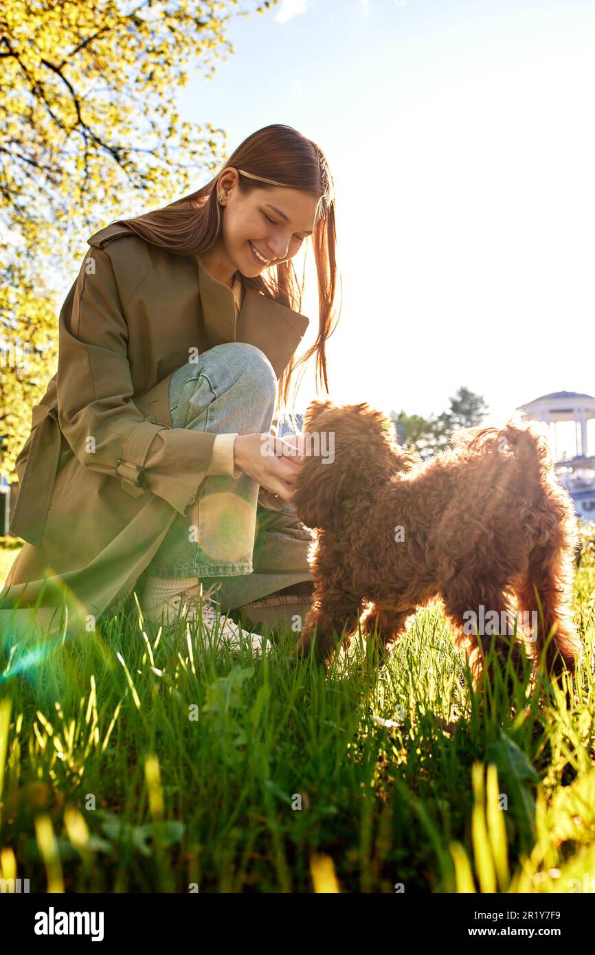 A young smiling blonde girl in jeans and a beige raincoat sits and ... A young smiling blonde girl in jeans and a beige raincoat sits and ...