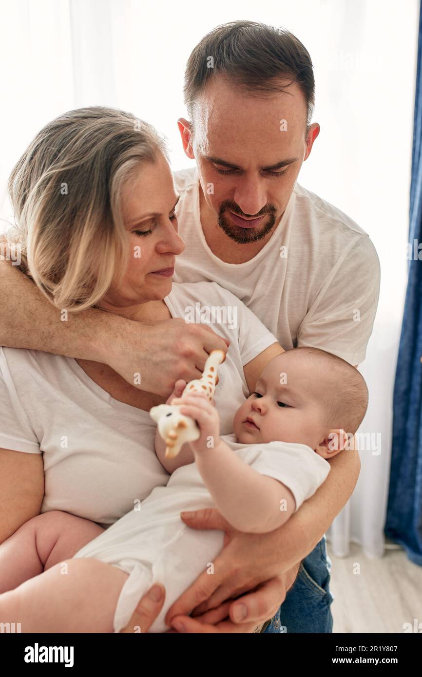 Mom and dad are playing with their little child in a bright room, all ...