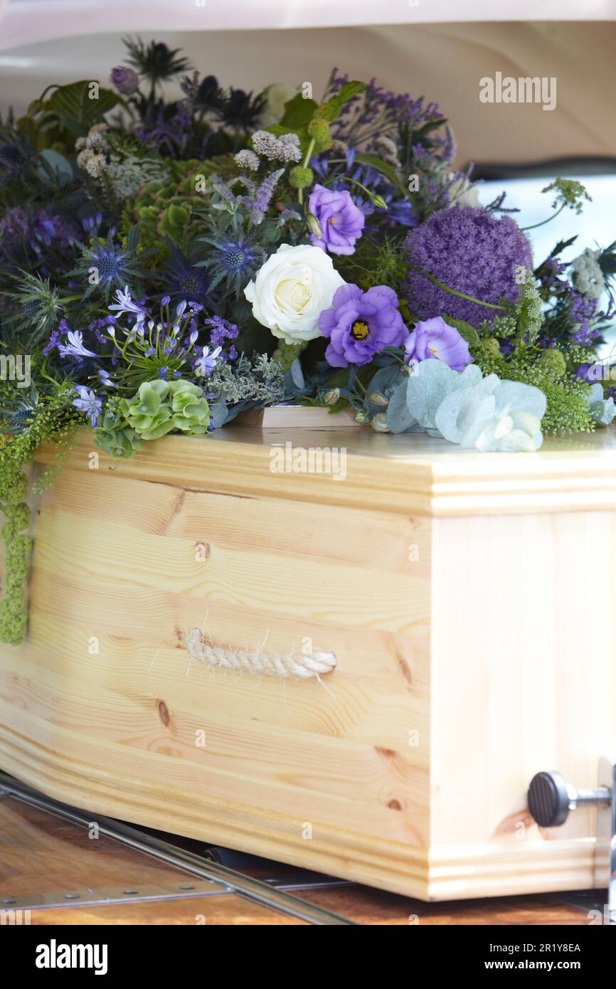 Close Up Of Plain Wooden Coffin With Floral Tributes In Back Of Hearse ...