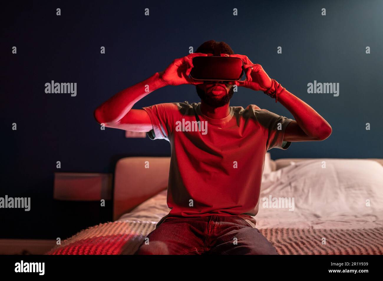 Black man using virtual reality headset at home with neon light, sit on ...