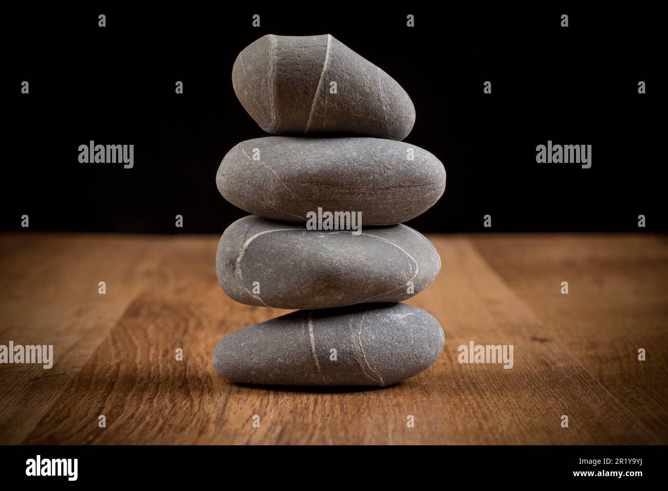 Piramid of four zen stones on wood and black background Stock Photo - Alamy