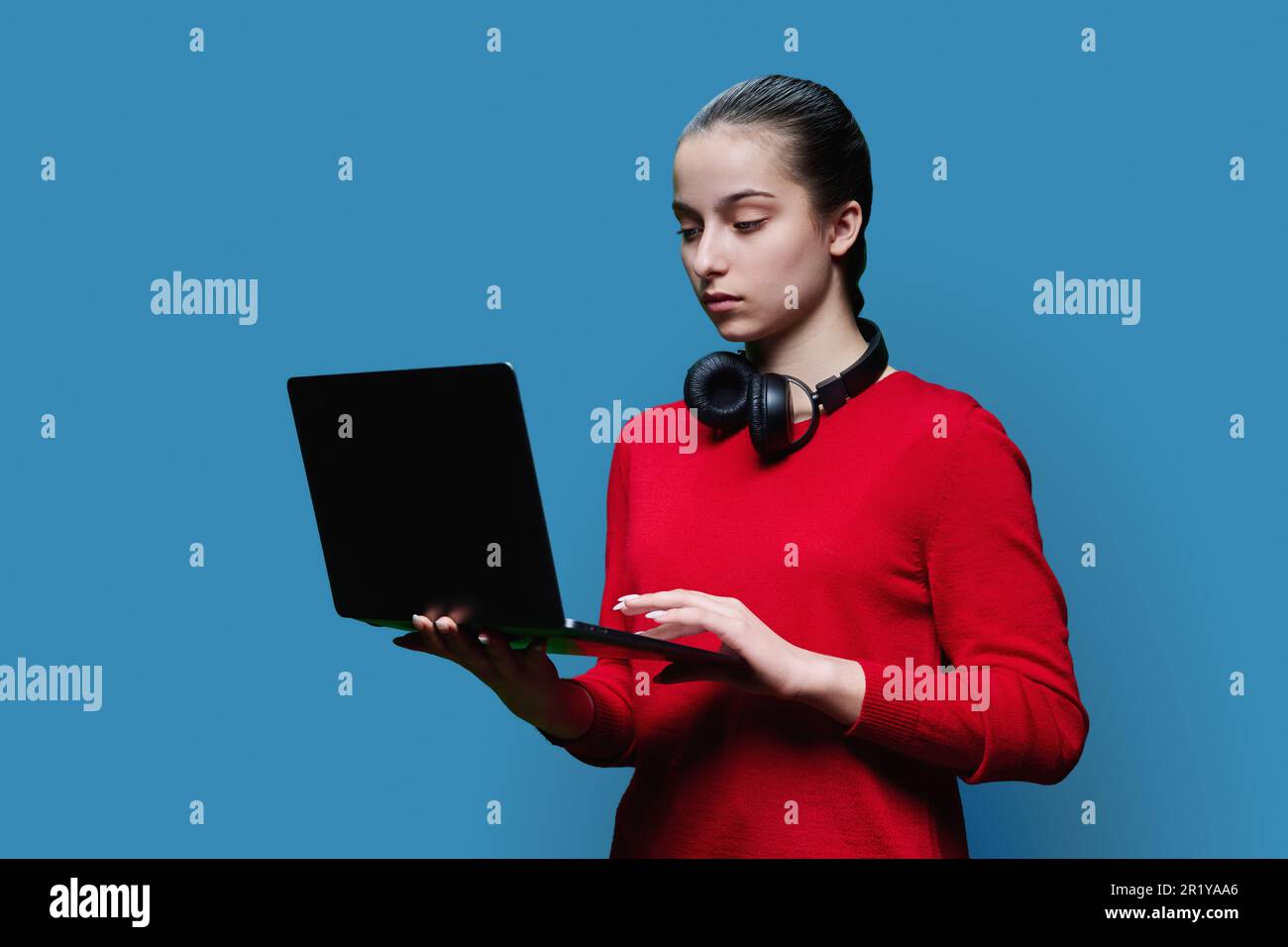 Teenage girl high school student using laptop on blue background Stock ...