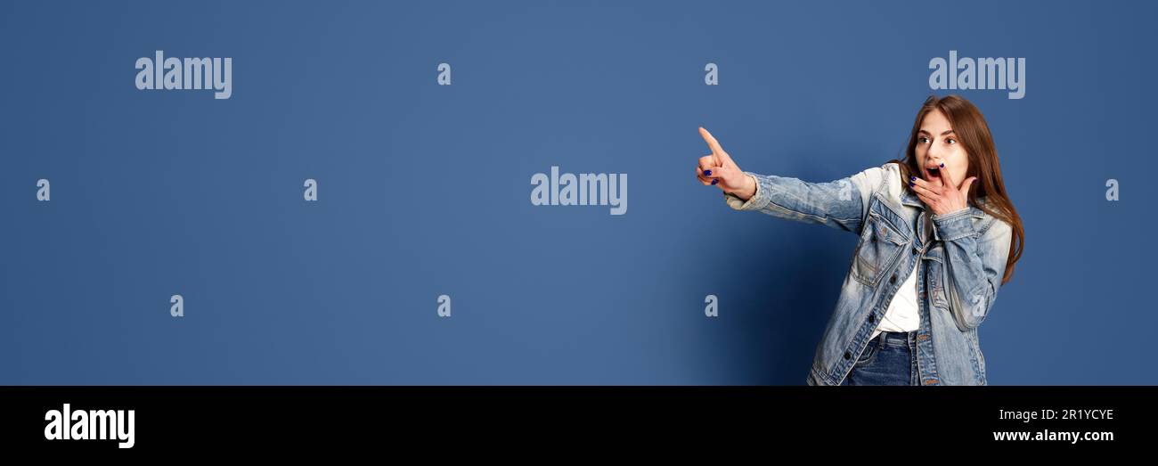 Portrait of astonished young girl pointing with finger and open mouth ...