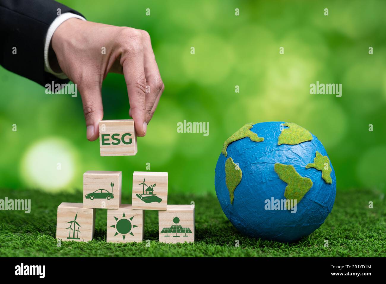 Businessman holding paper earth planet with ESG symbol wooden cube ...