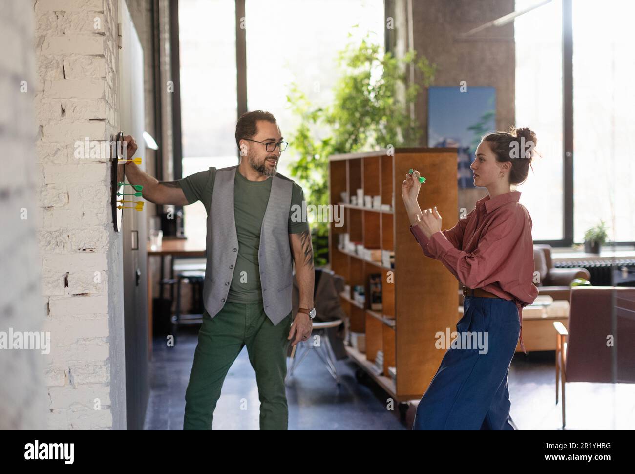 Happy colleagues having break at work, playing darts Stock Photo - Alamy