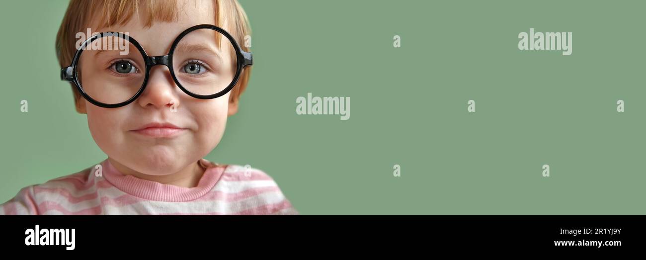 Funny child wearing round glasses on green studio background. Little ...