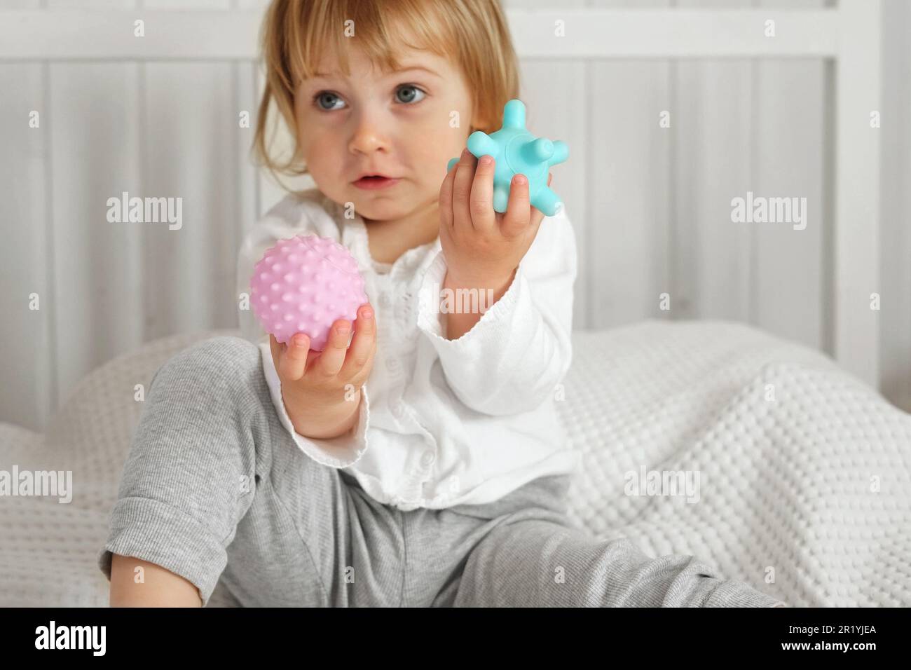 Cute baby girl playing tactile knobby balls. Young child hand plays ...