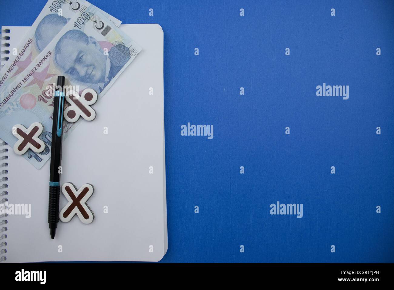 A notebook, Turkish lira, pen and math signs are placed on the edge of ...