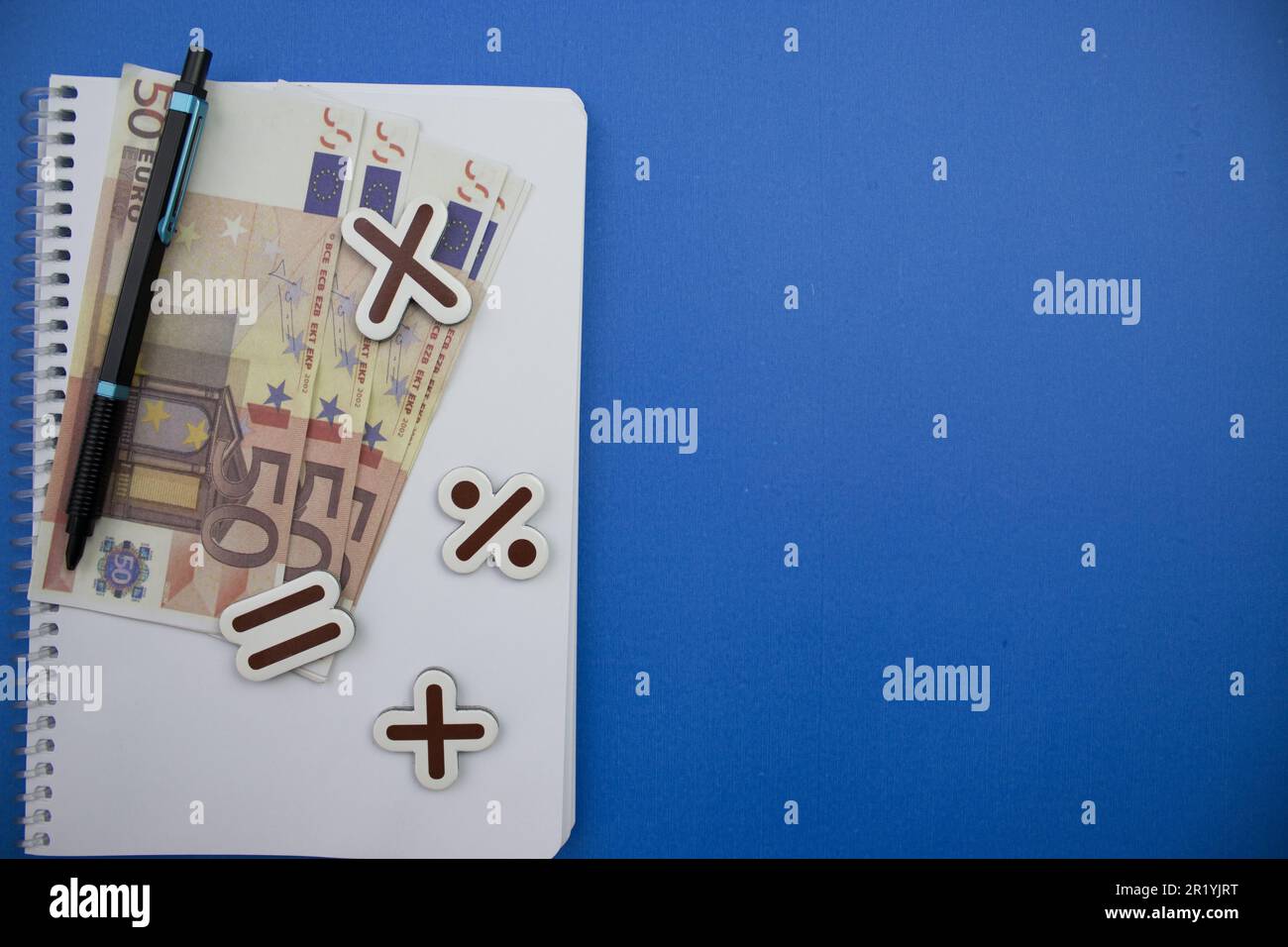 Placed on the edge of the blue background, notebook, euros, pencil and ...