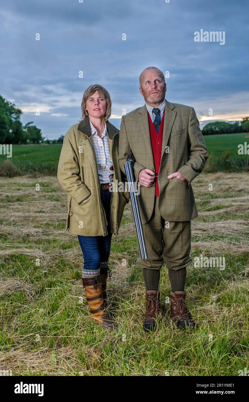 An English lady and gentleman stood at twilight in shooting suits with ...