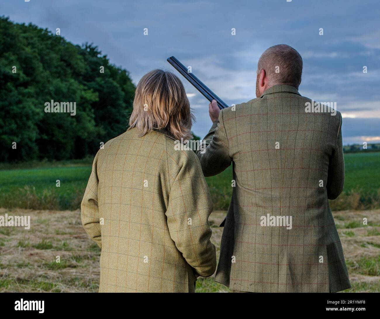 An English lady and gentleman stood at twilight in shooting suits with ...