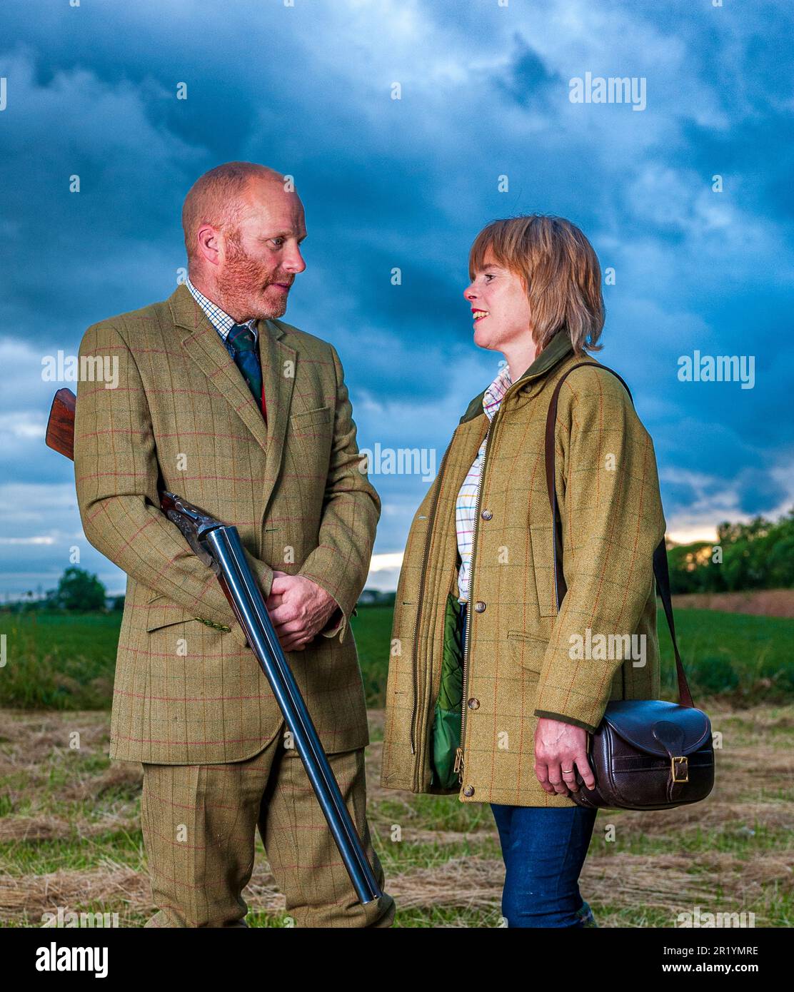 An English lady and gentleman stood at twilight in shooting suits with ...
