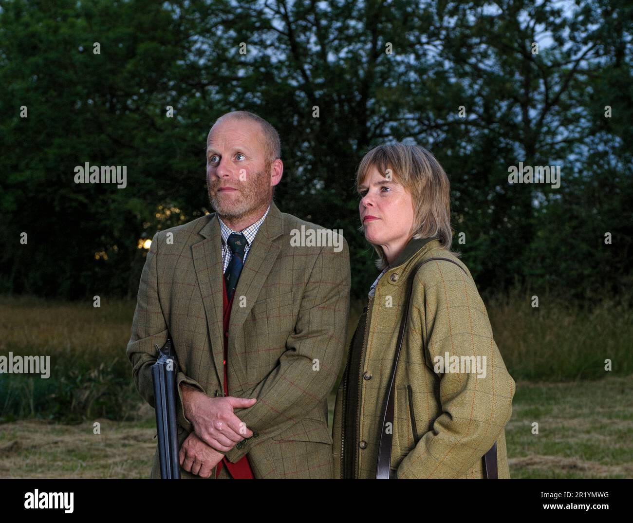 An English lady and gentleman stood at twilight in shooting suits with ...