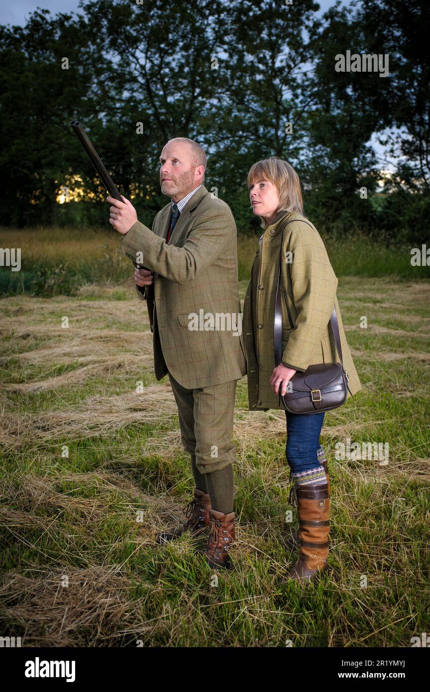 An English lady and gentleman stood at twilight in shooting suits with ...