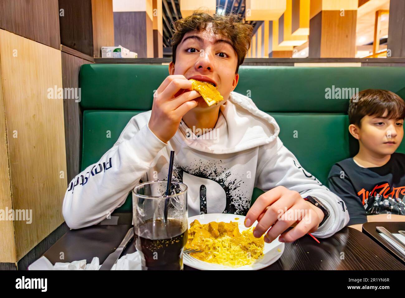 A teenage boy eating curry, rice and naan bread at an asian buffet food ...