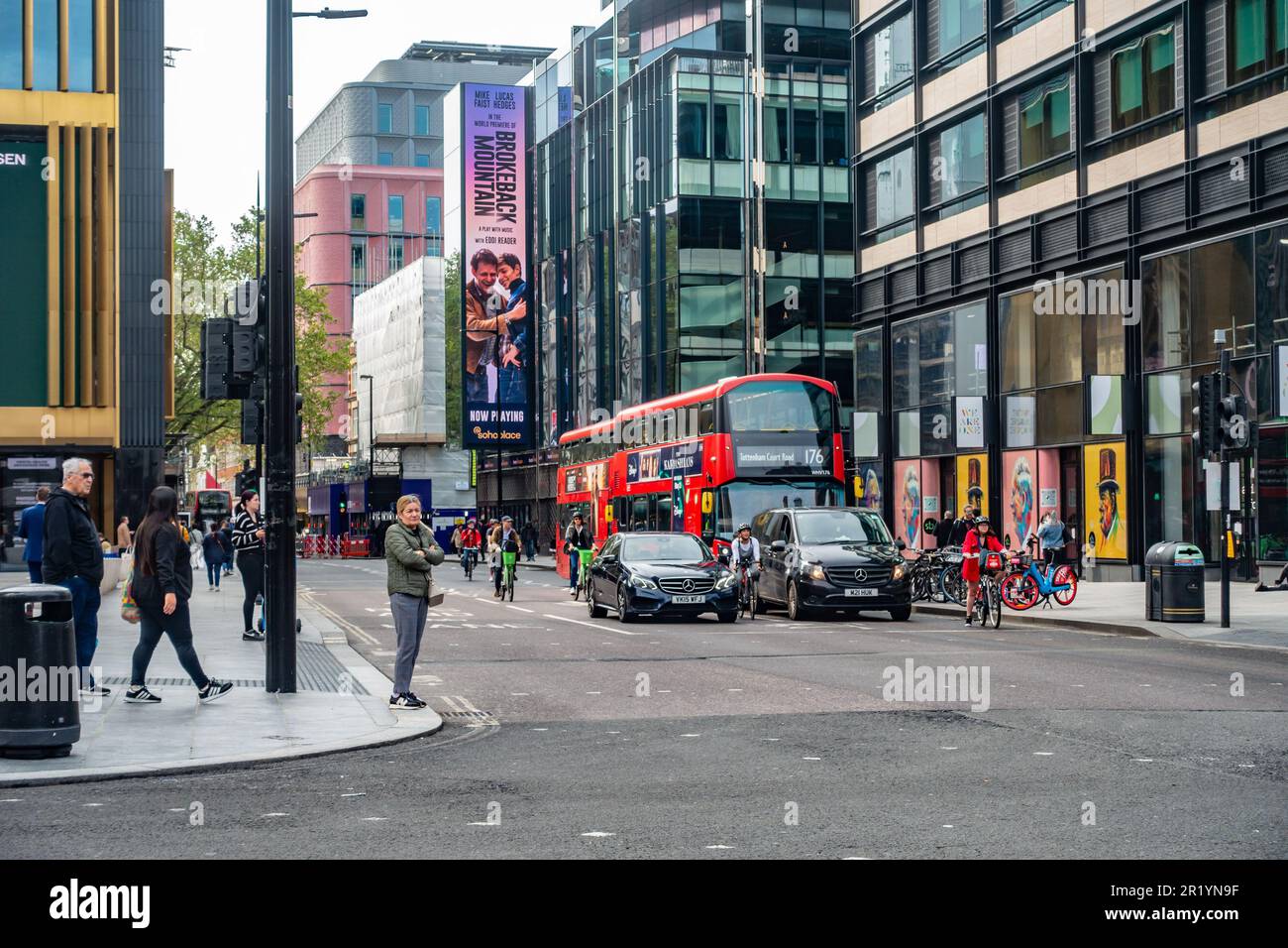 A couple of red, London double decker buses wait at traffic lights on ...