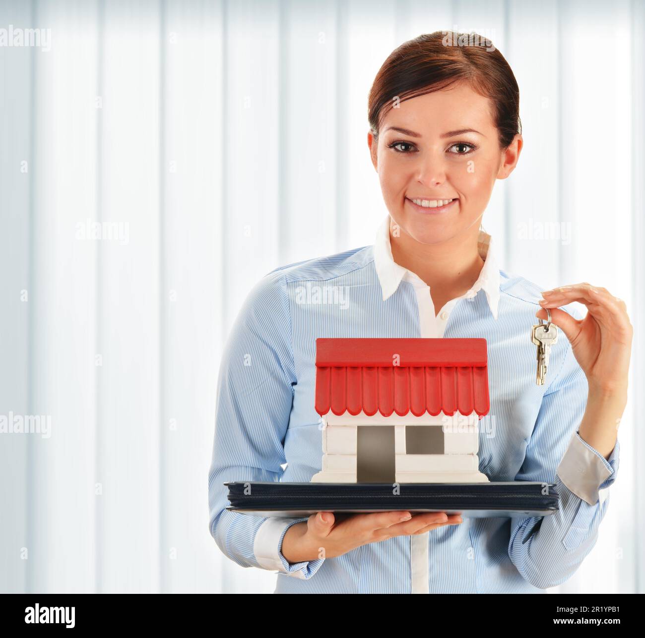 Young woman holding small house and keys Stock Photo - Alamy