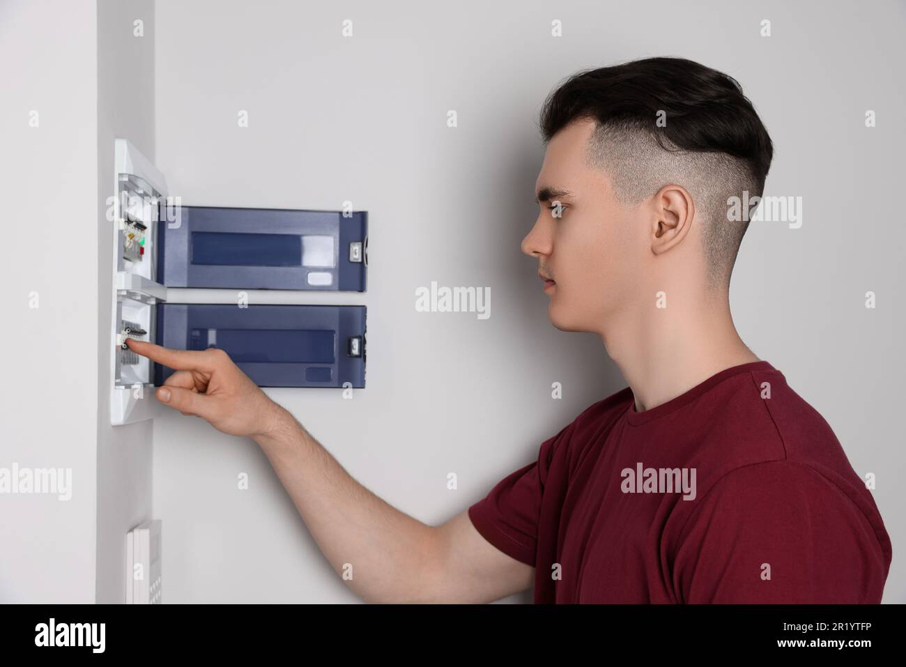 Young handyman pressing switch on electrical panel board indoors Stock ...