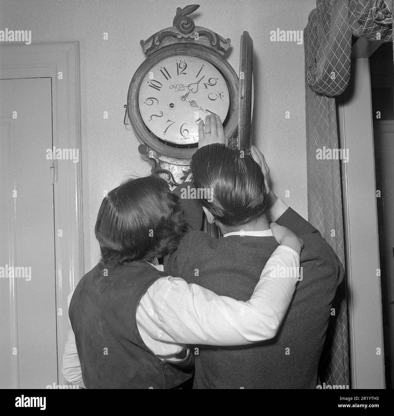 In the 1950s. A woman and a man in front of a antique clock with the ...