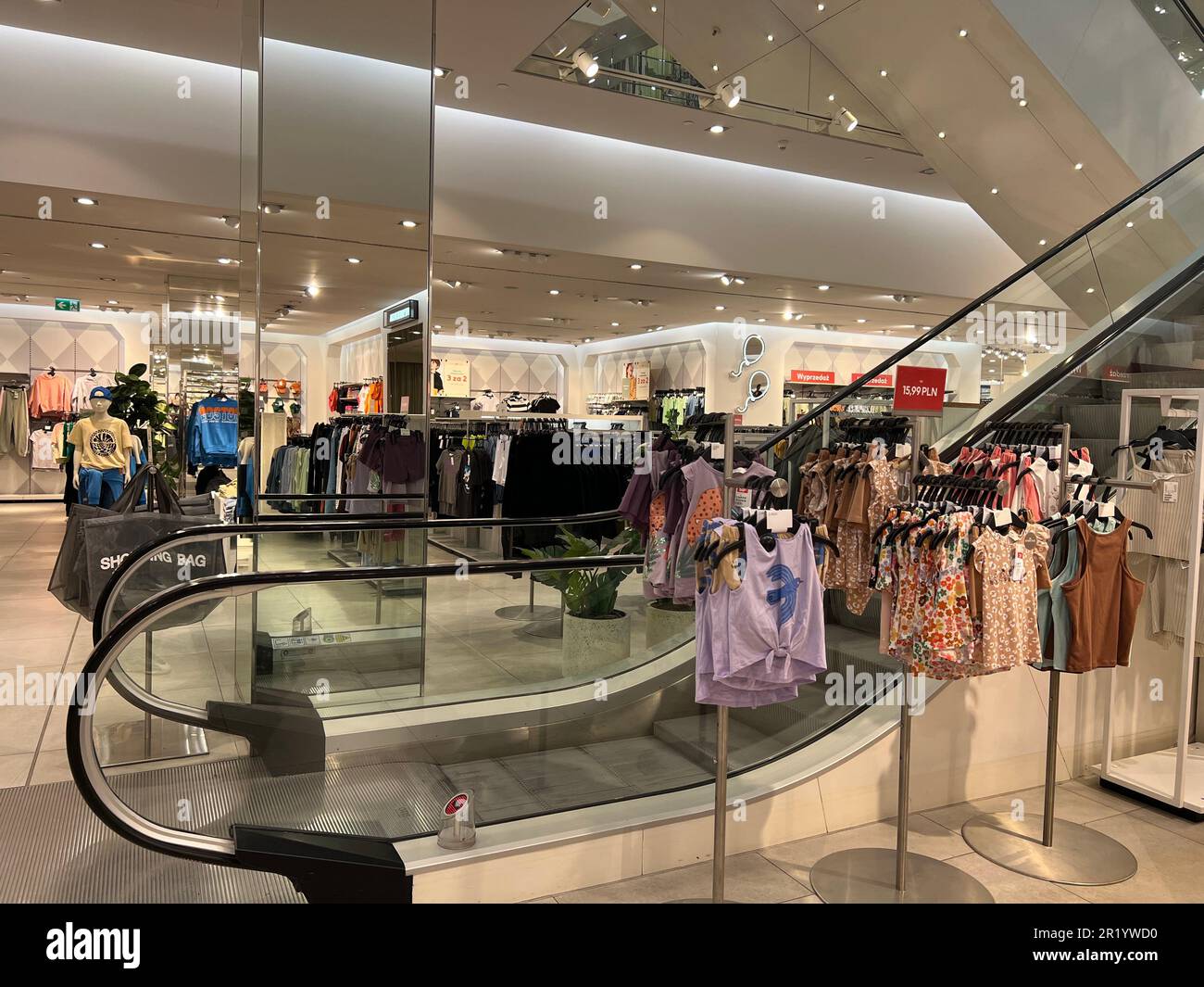 Racks with stylish clothes and escalator in shopping mall Stock Photo ...