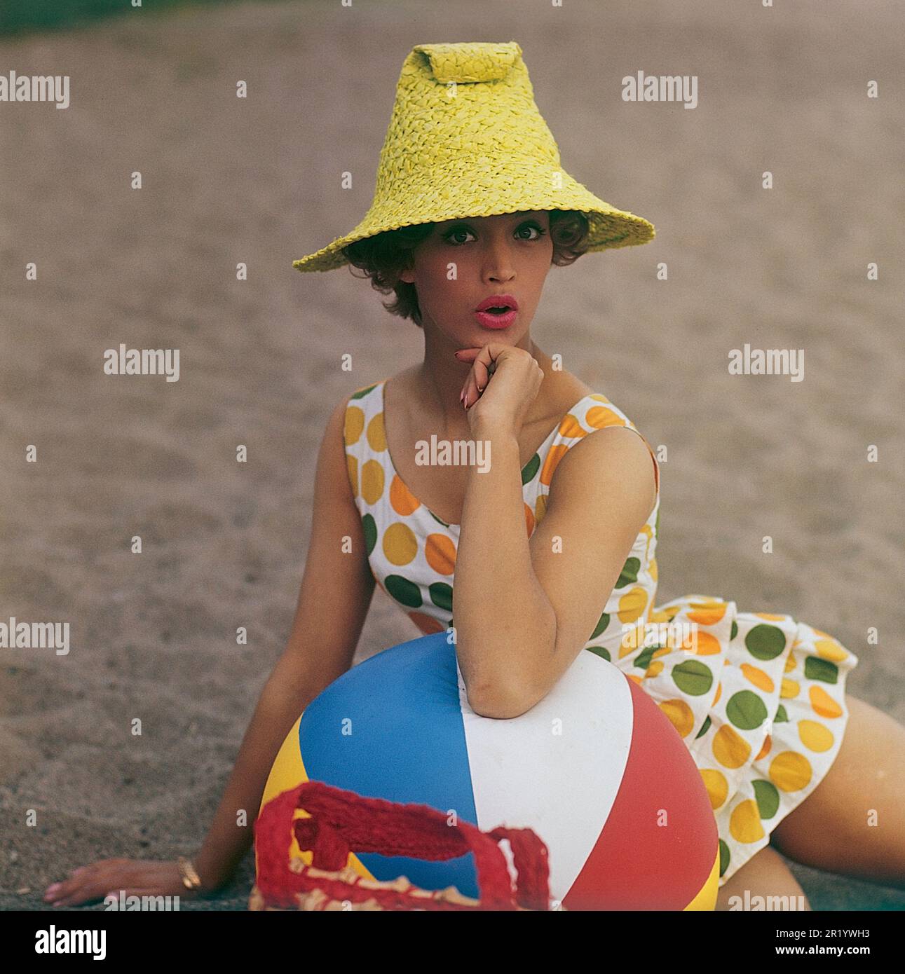 1960s woman. A young woman wearing a colorful summer dress and sunhat ...