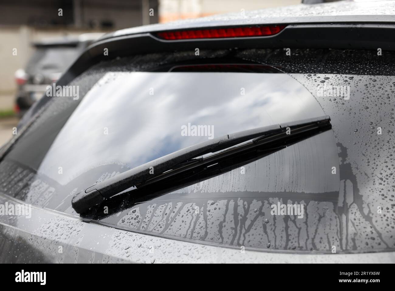 Car wiper cleaning water drops from rear windshield glass outdoors ...