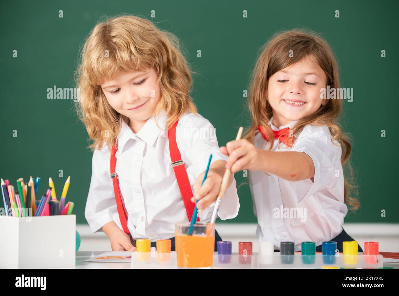 School children drawing a colorful pictures with pencil crayons in ...