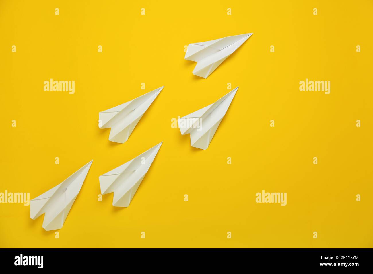 Many white handmade paper planes on yellow background. Space for text ...