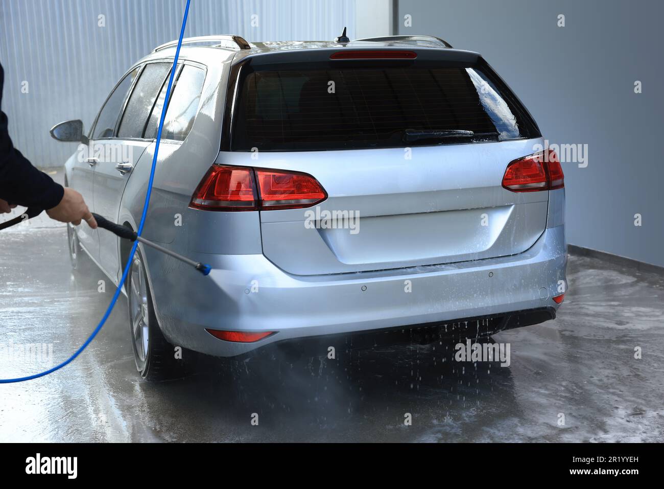 Man washing auto with high pressure water jet at outdoor car wash ...