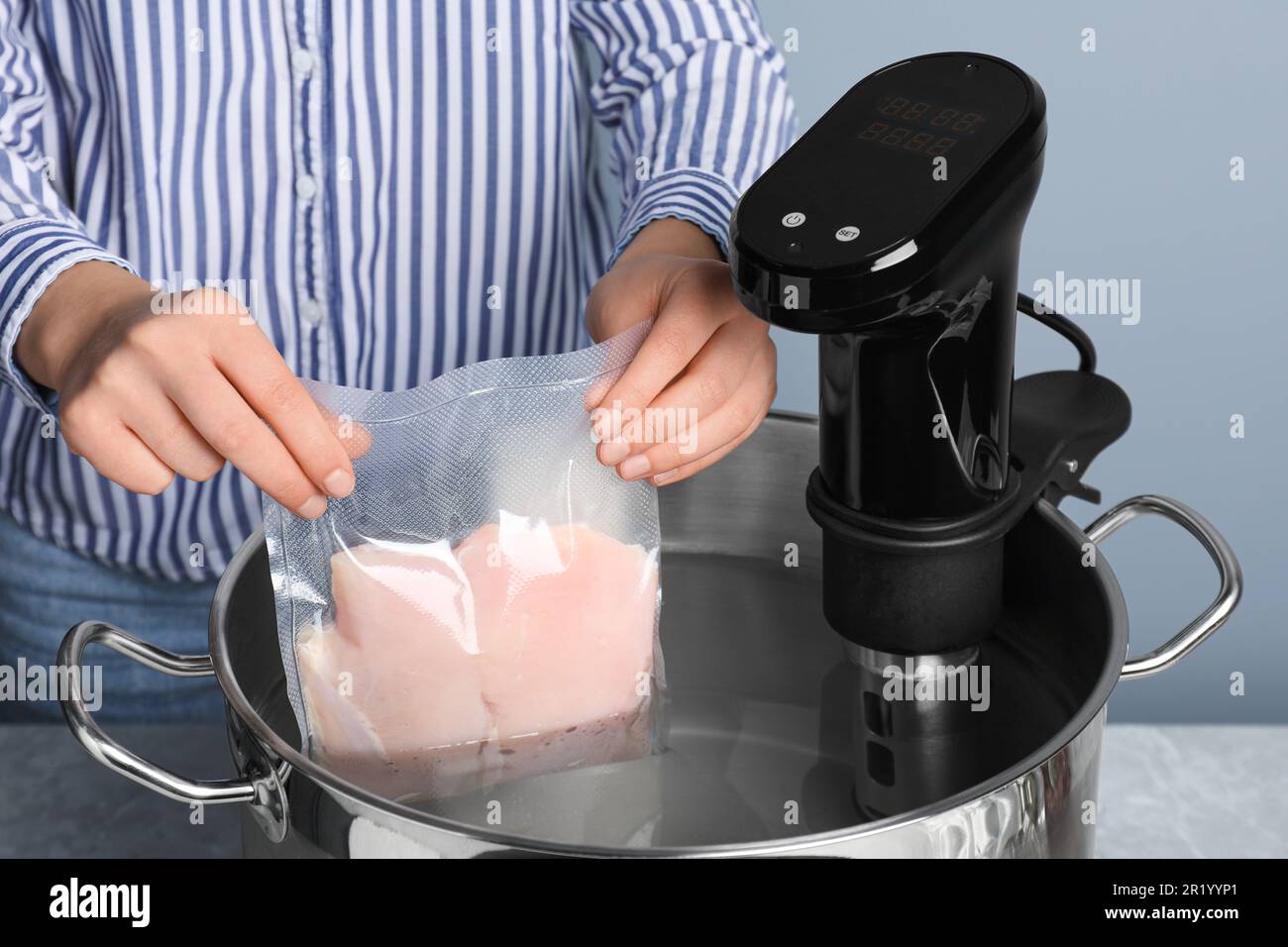 Woman putting vacuum packed meat into pot with thermal immersion ...