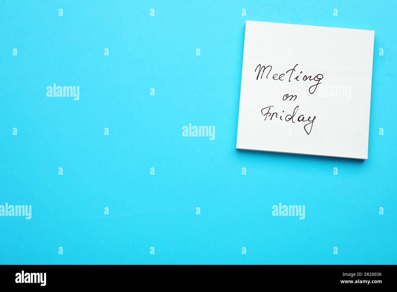 Paper note with words Meeting on Friday against blue background, top ...
