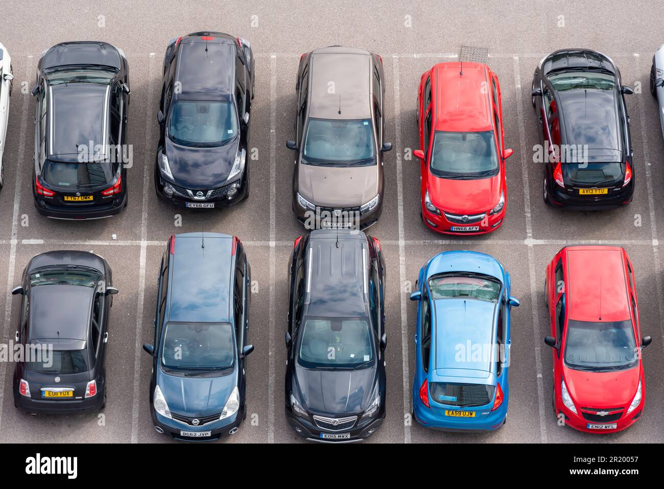 Cars parked in a car park, viewed from above. Marked out parking bays, all taken by a parked car ...